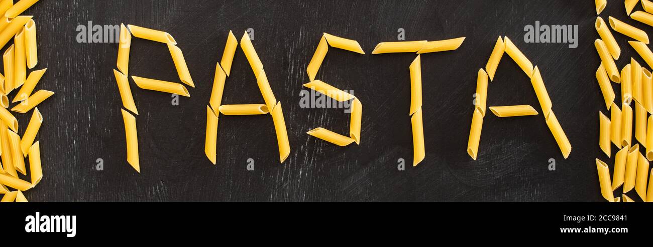 top view of pasta word made of raw penne on black background, panoramic ...