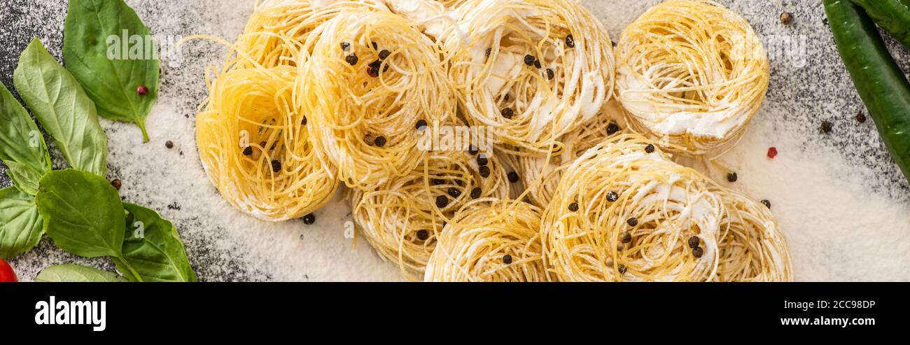 top view of raw Capellini pasta with basil, spices and flour, panoramic ...