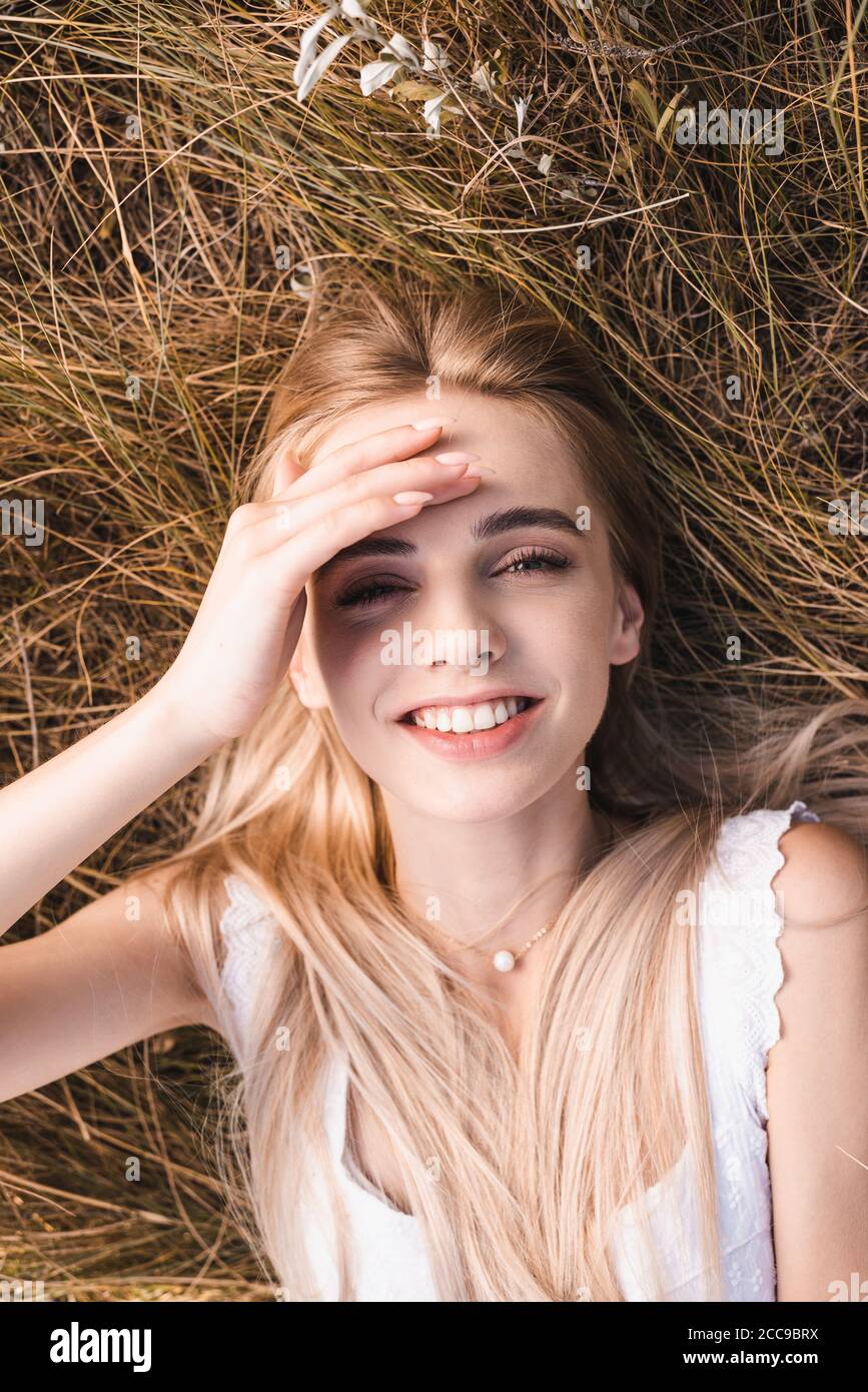 top view of excited blonde woman touching forehead and looking at ...