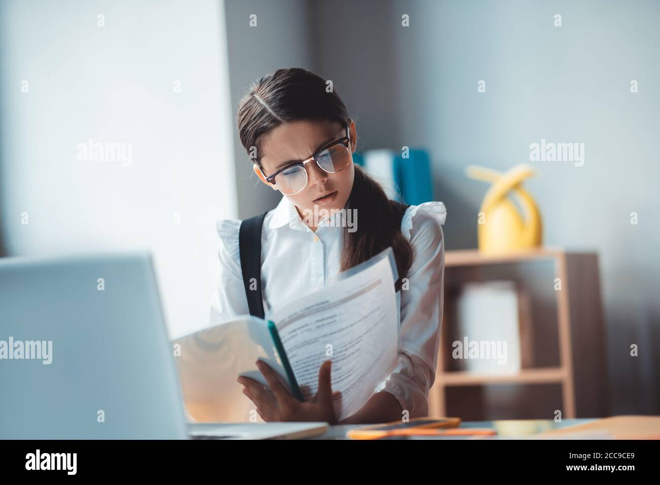 Brunette girl in eyeglasses reading a report and looking involved Stock ...