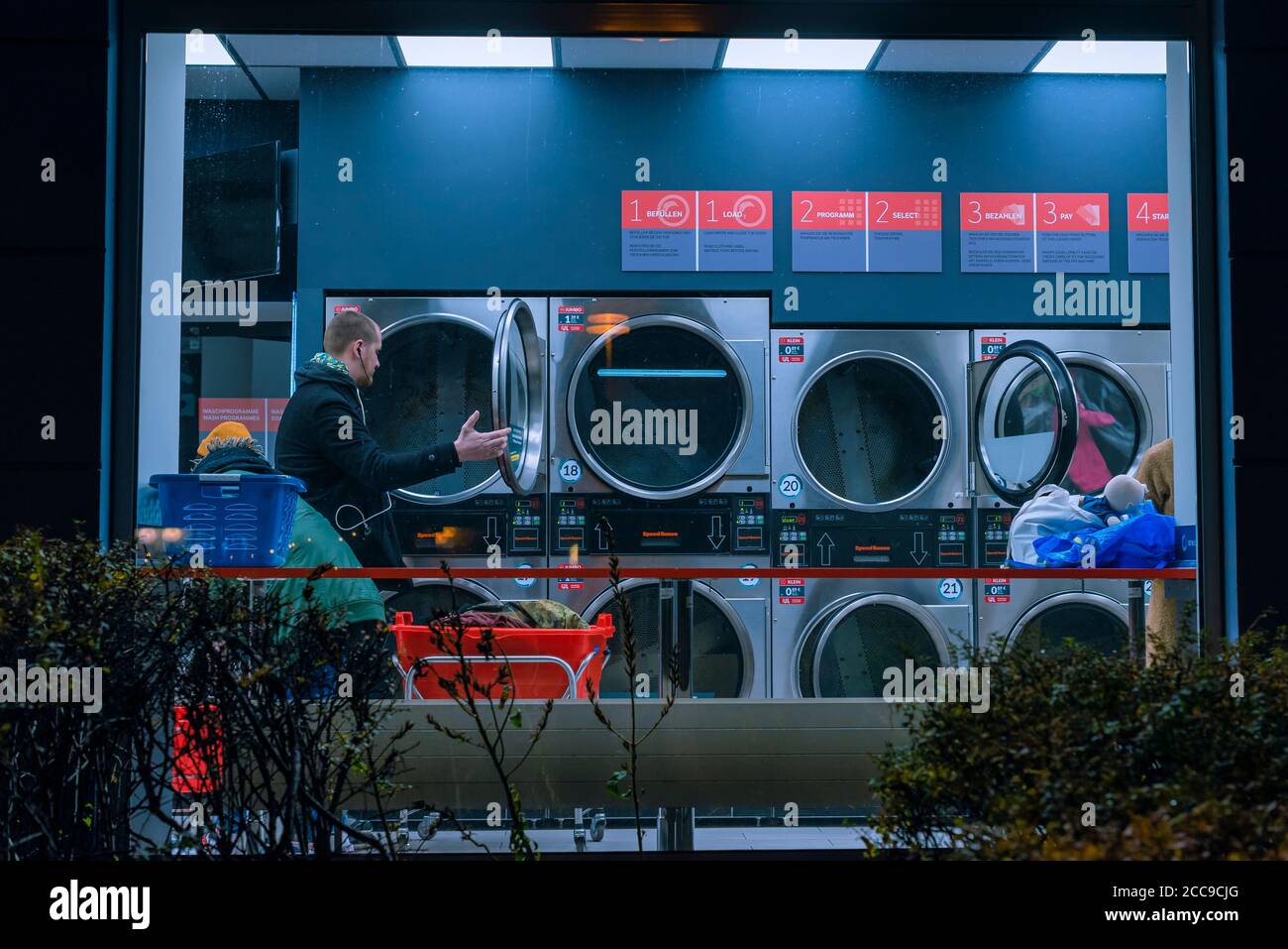 A man in a laundromat, laundromat photographed from the outside, shop ...