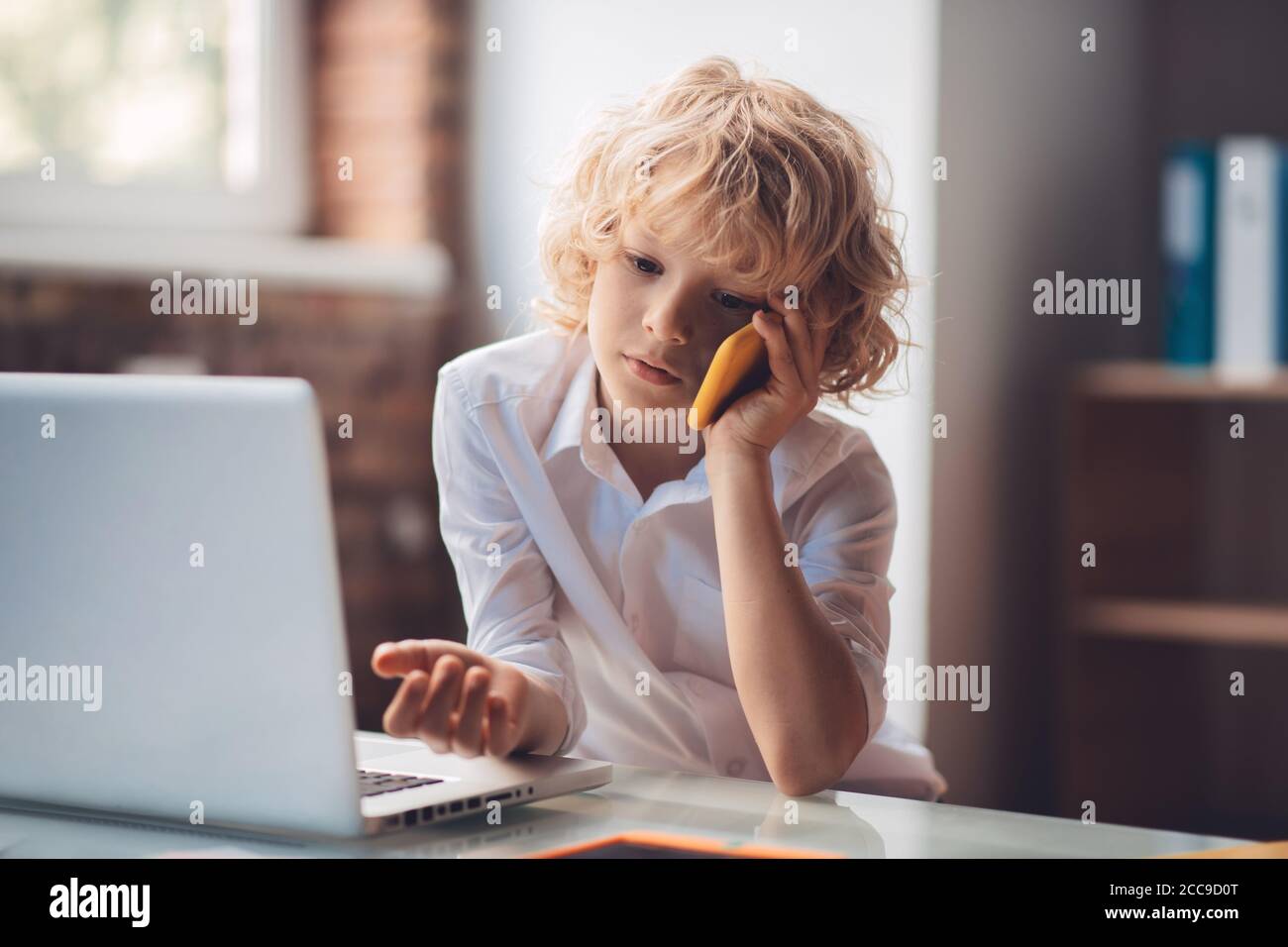 Cute blonde boy sitting and talking on the phone Stock Photo - Alamy