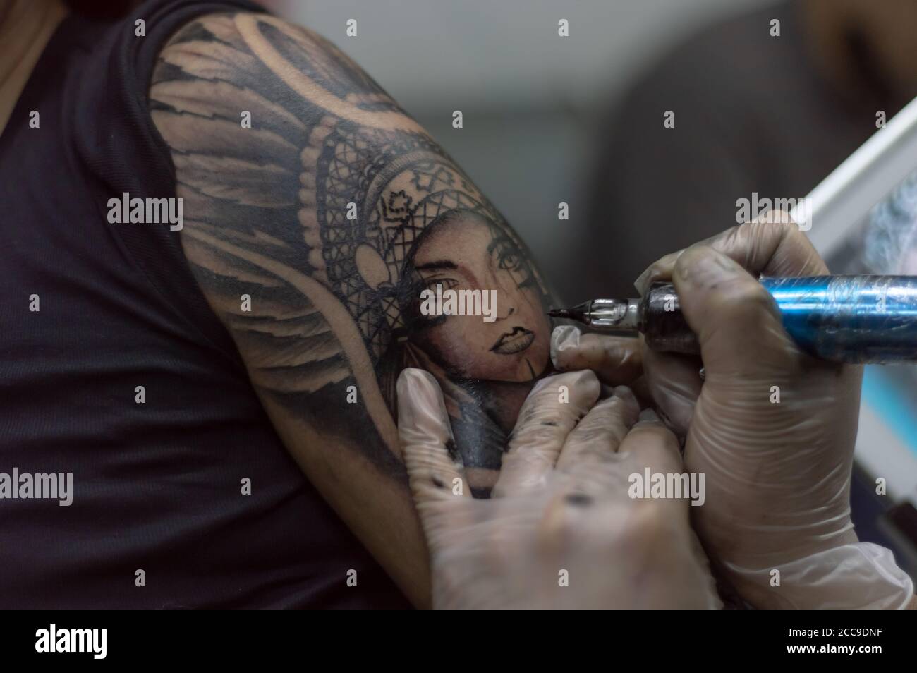 Closeup shot tattoo artist holding a tattoo machine tattooing a person ...