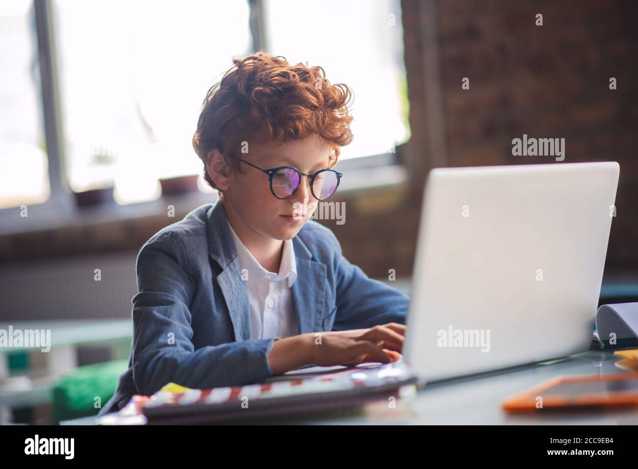 Red-haired boy sitting at the laptop and looking busy Stock Photo - Alamy