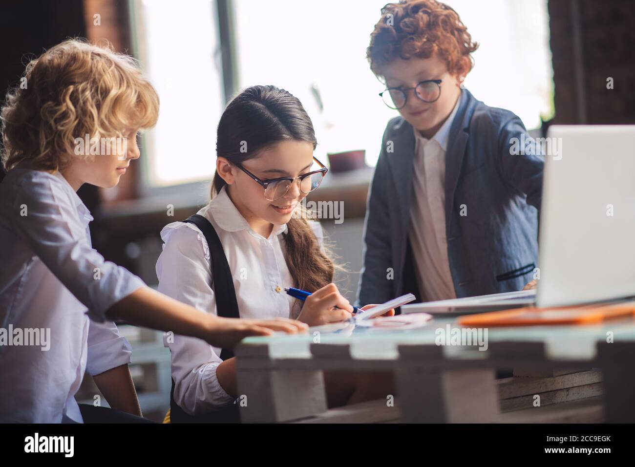 Three cute kids working on lessons together and looking involved Stock ...