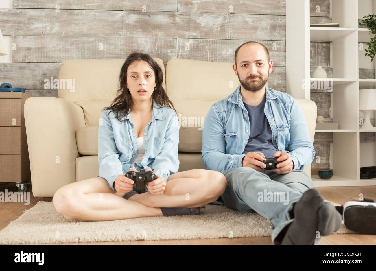 Couple having fun at home playing video games with wireless controller ...