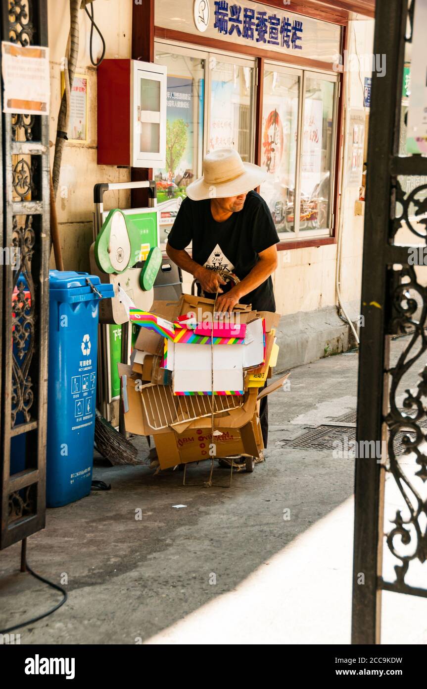 An old man collecting cardboard from household waste to sell in central ...