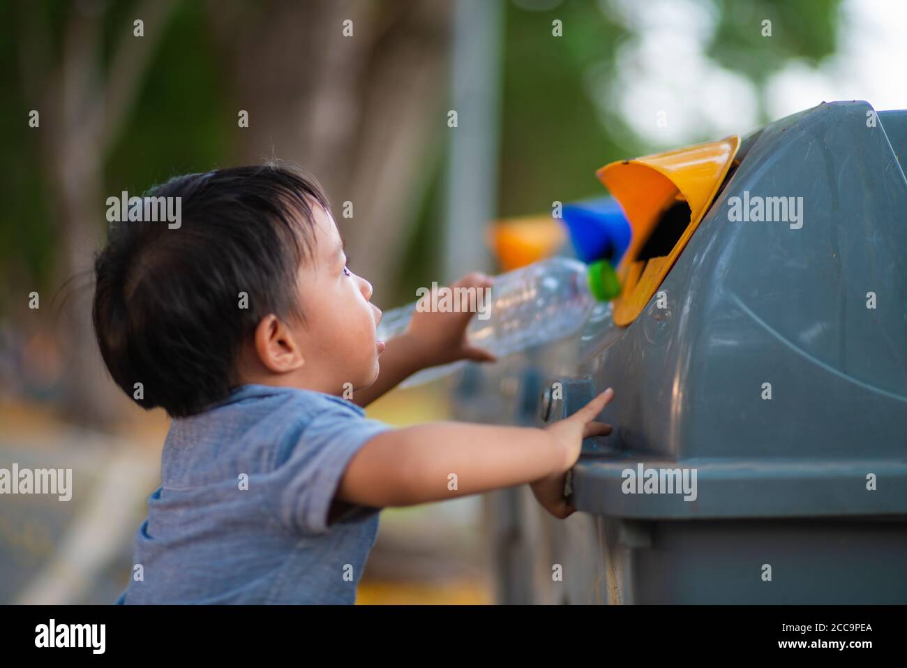 Little asian toddler baby boy throwing plastic bottle in recycling ...