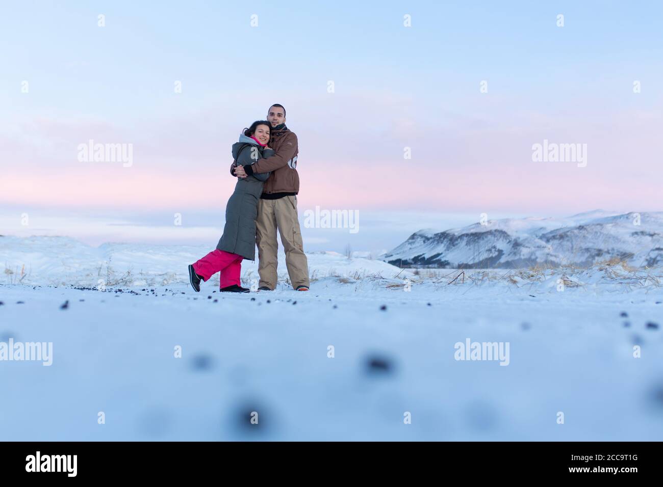 Couple hugs in a snowy field at sunrise Stock Photo - Alamy