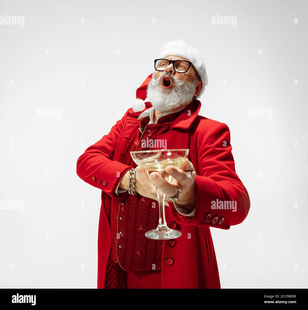 Cheers, toast. Modern stylish Santa Claus in red fashionable suit ...
