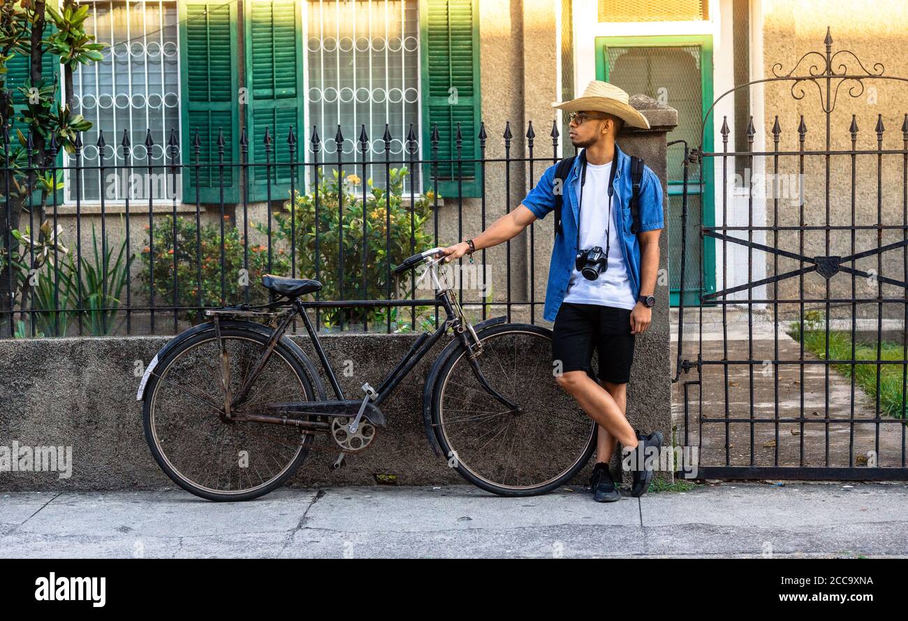 Male traveler with a photo camera and bicycle standing on the street ...