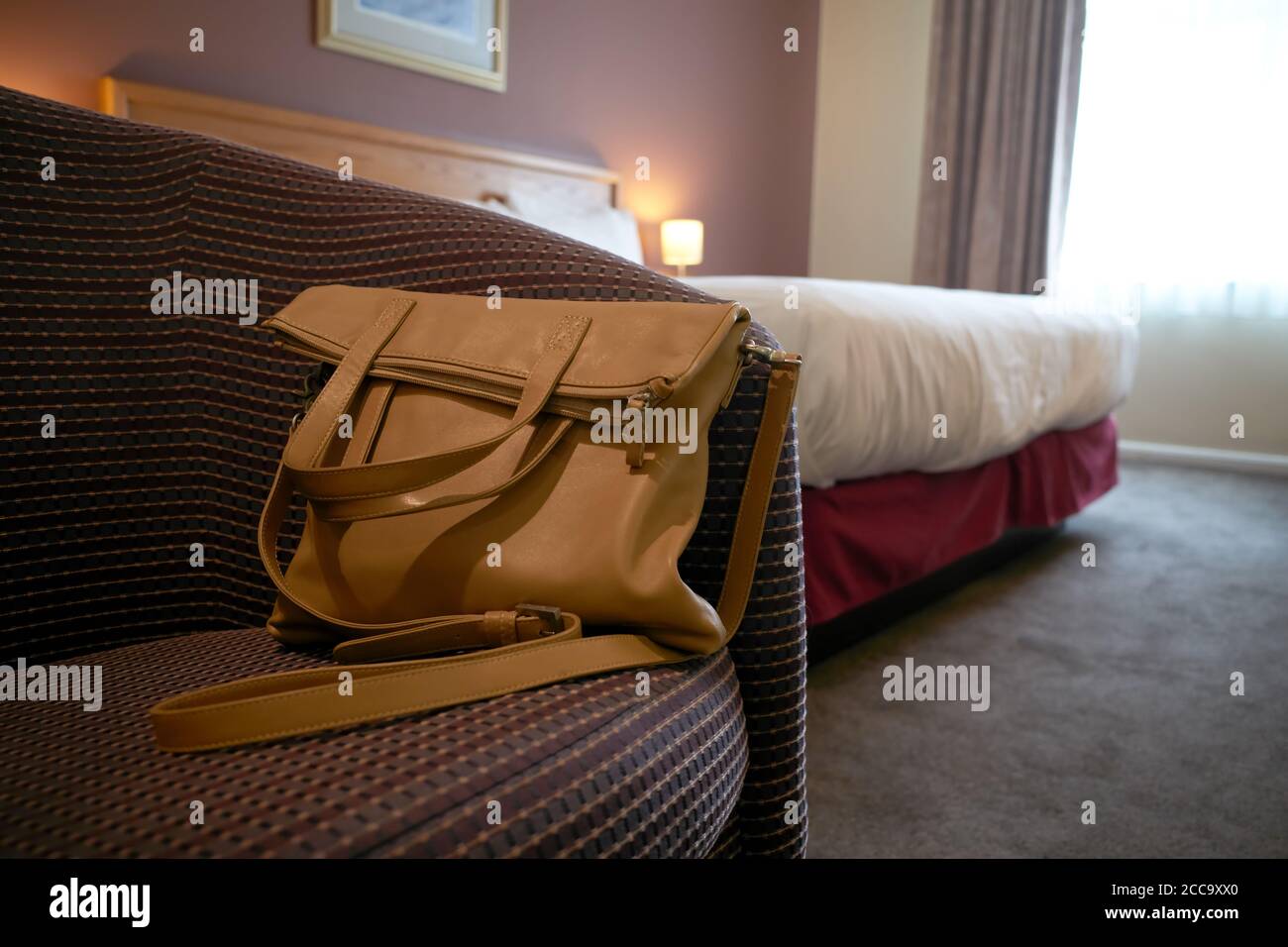 A photograph of a handbag on a chair in a hotel room Stock Photo - Alamy