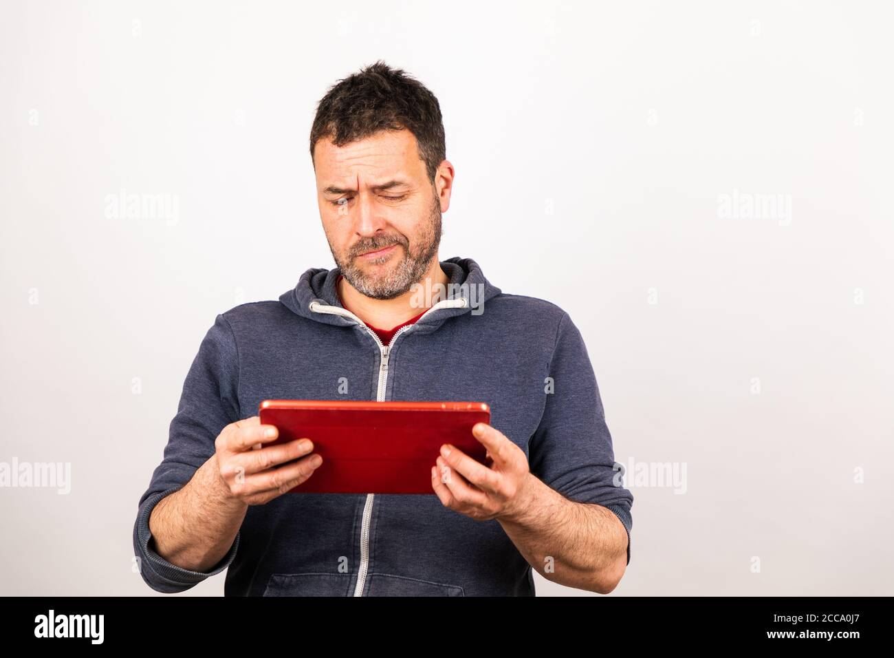 Caucasian male looking at a tablet with a displeased look isolated on a ...