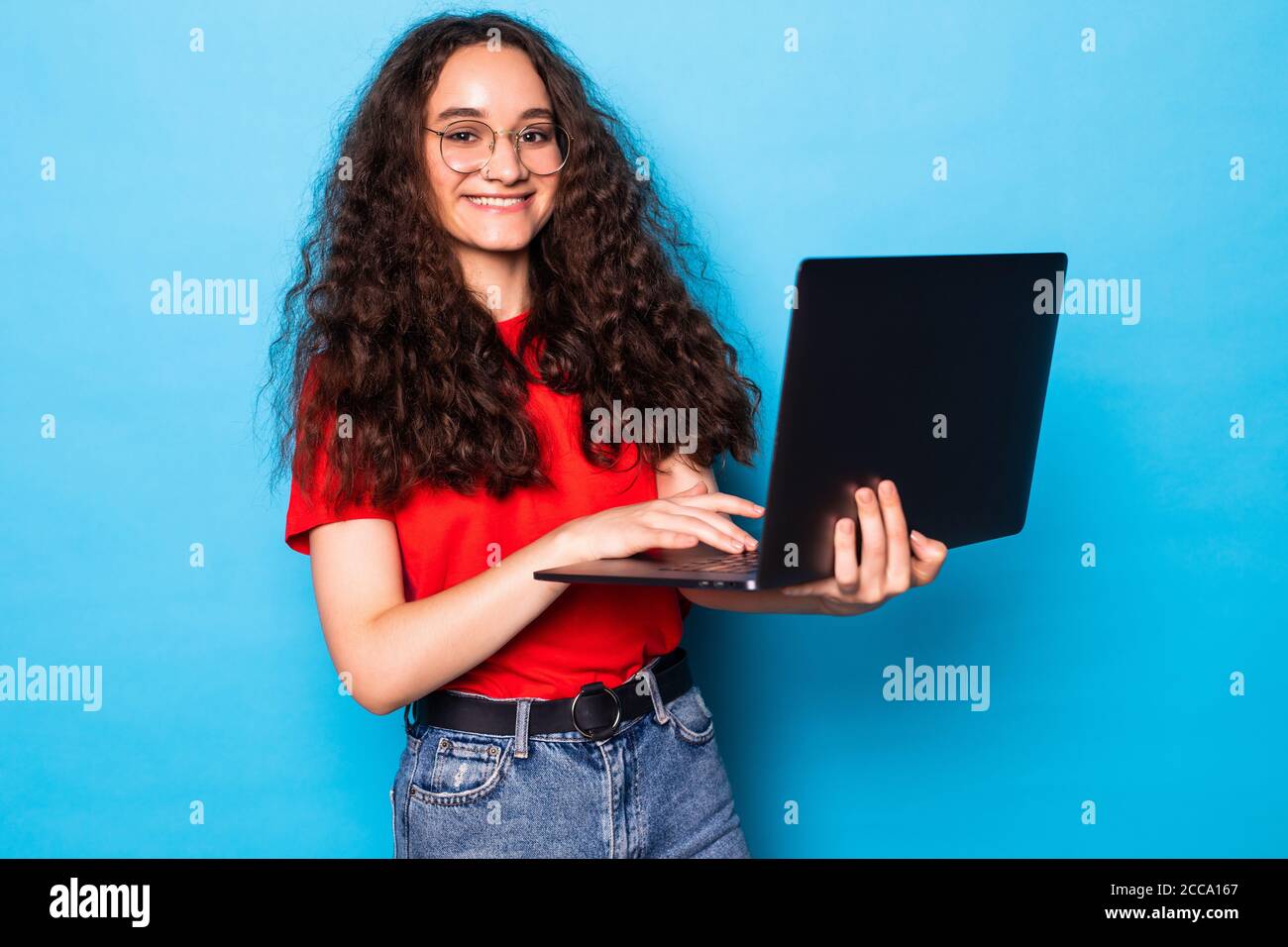 Portrait of a beautiful girl pointing finger at blank screen laptop ...