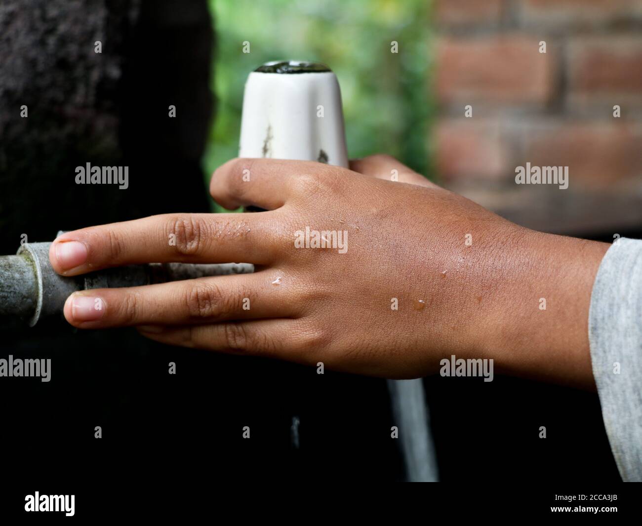 Hand of a boy turning on an old plastic water tap, vintage Stock Photo ...