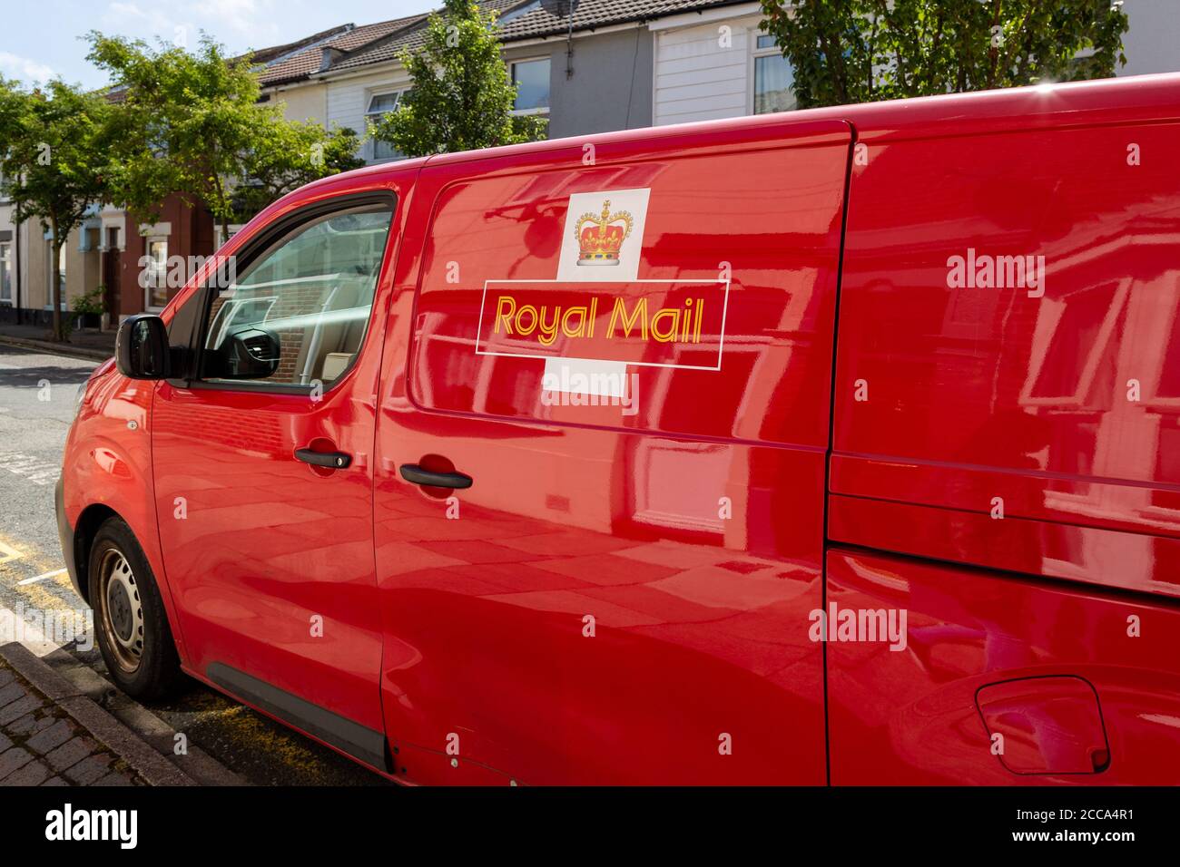 the side of a red Royal mail van with houses reflecting in the ...