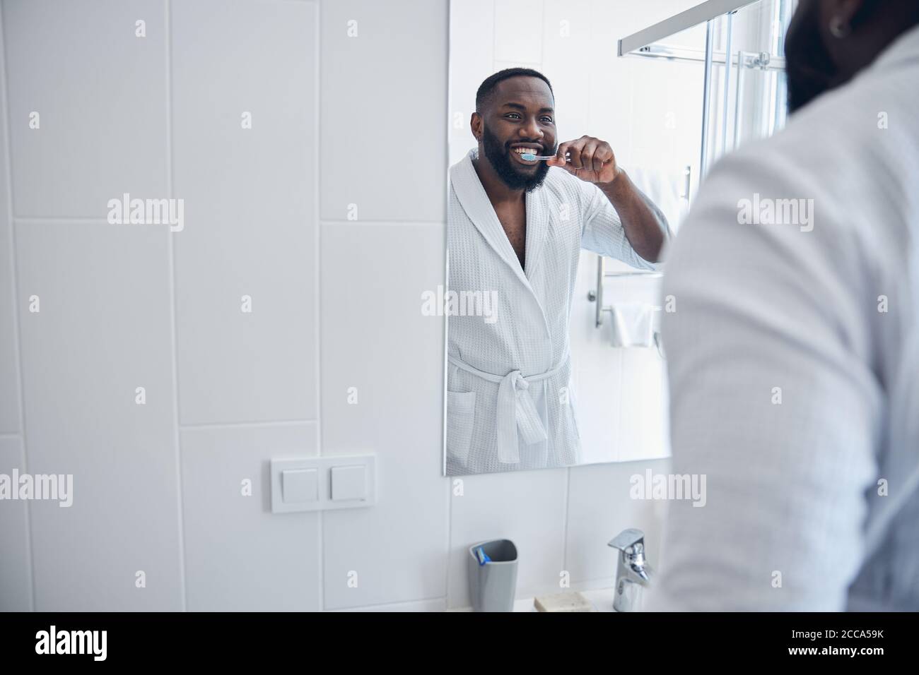 Positive delighted dark-skinned man looking at his reflection Stock ...