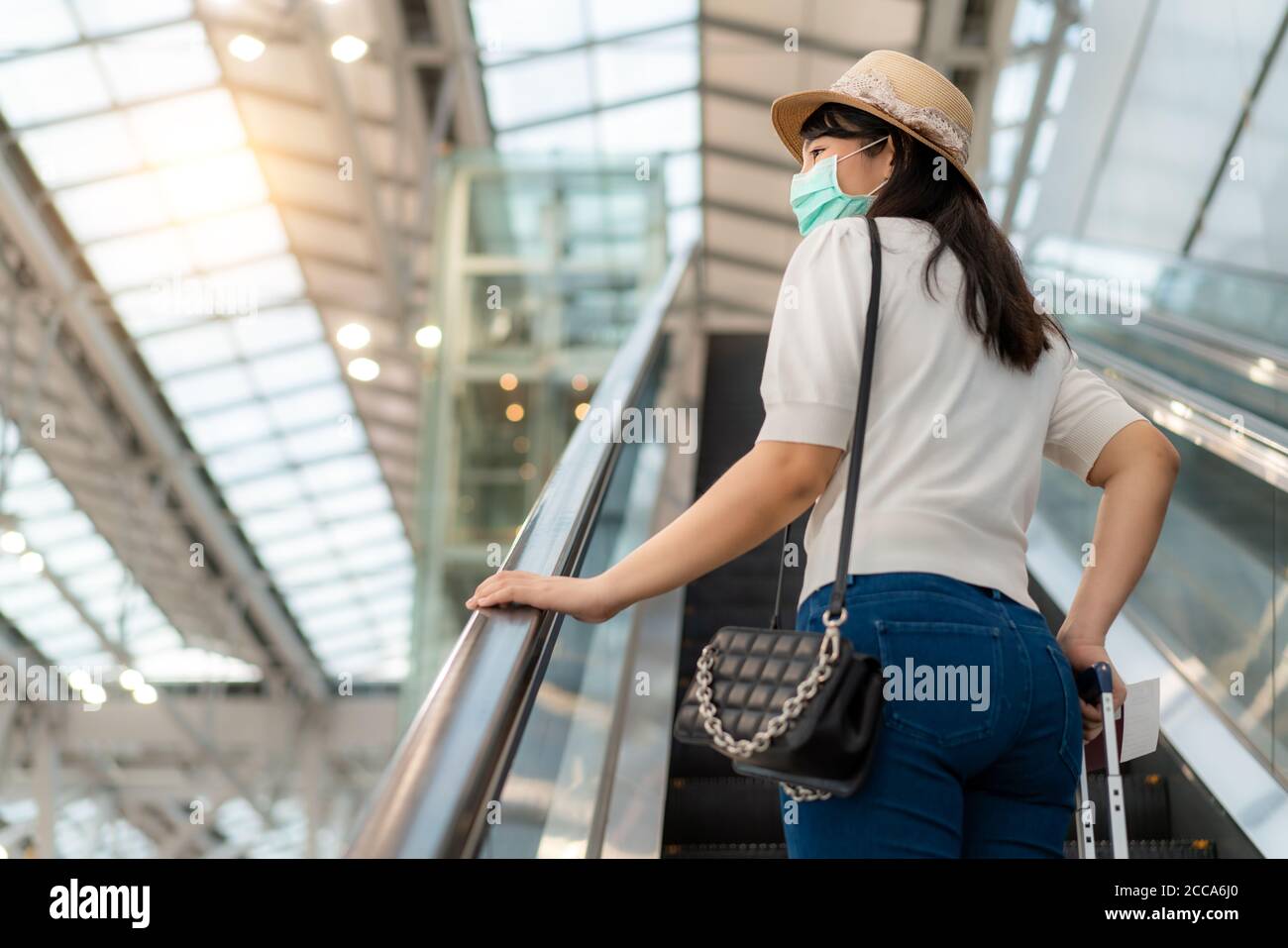 Asian traveler woman with luggage wearing face mask looking outside ...