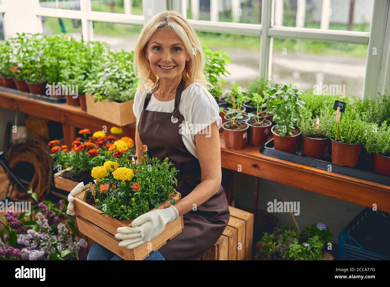 Happy woman botanist sitting on a crate Stock Photo - Alamy