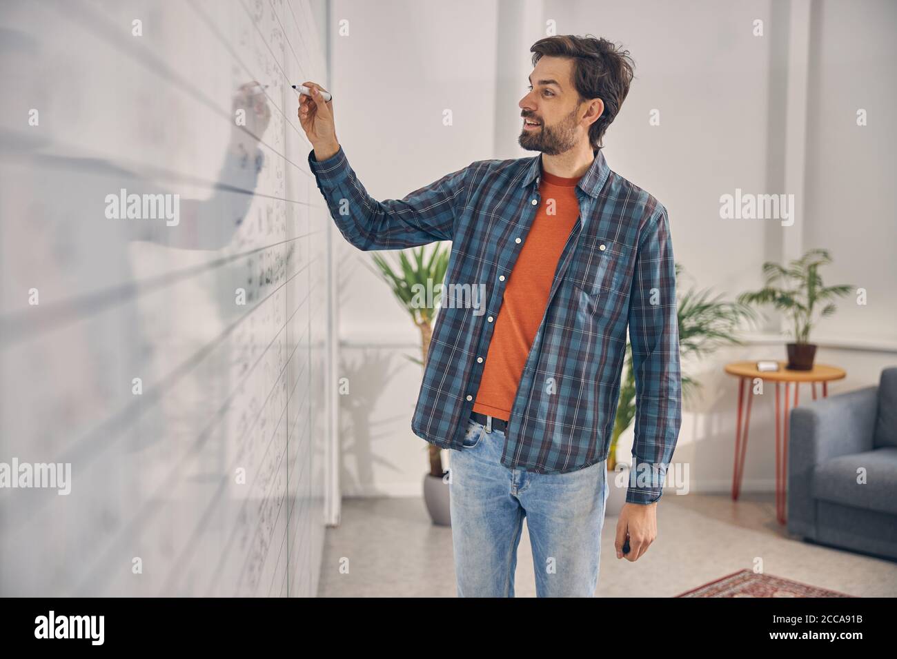 Cheerful male worker writing on whiteboard in office Stock Photo - Alamy