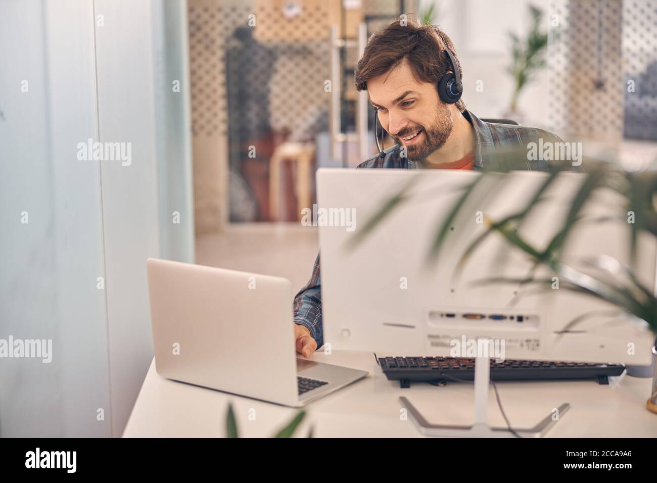 Cheerful young man using computer and laptop at work Stock Photo - Alamy