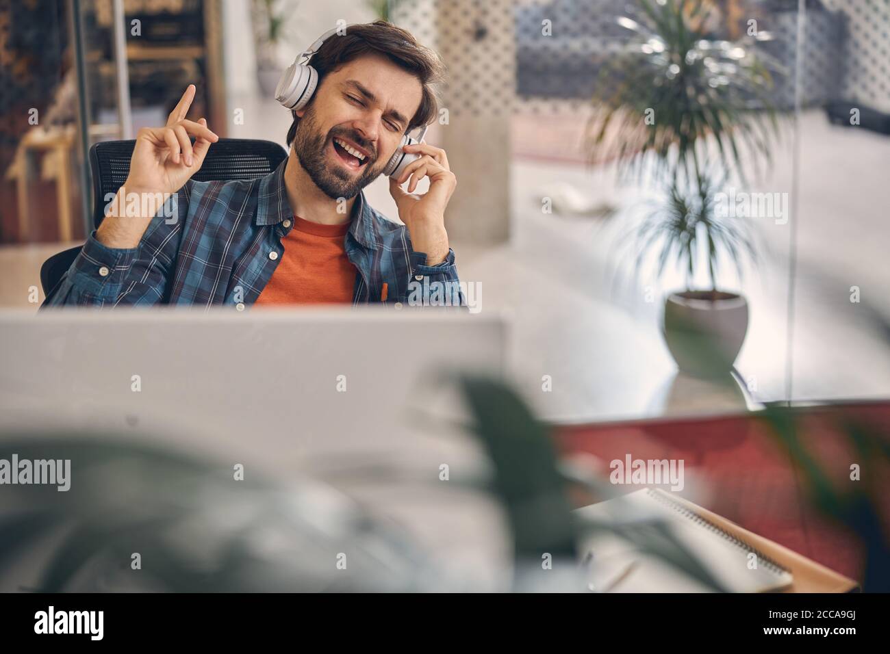 Cheerful young man listening to music at work Stock Photo - Alamy