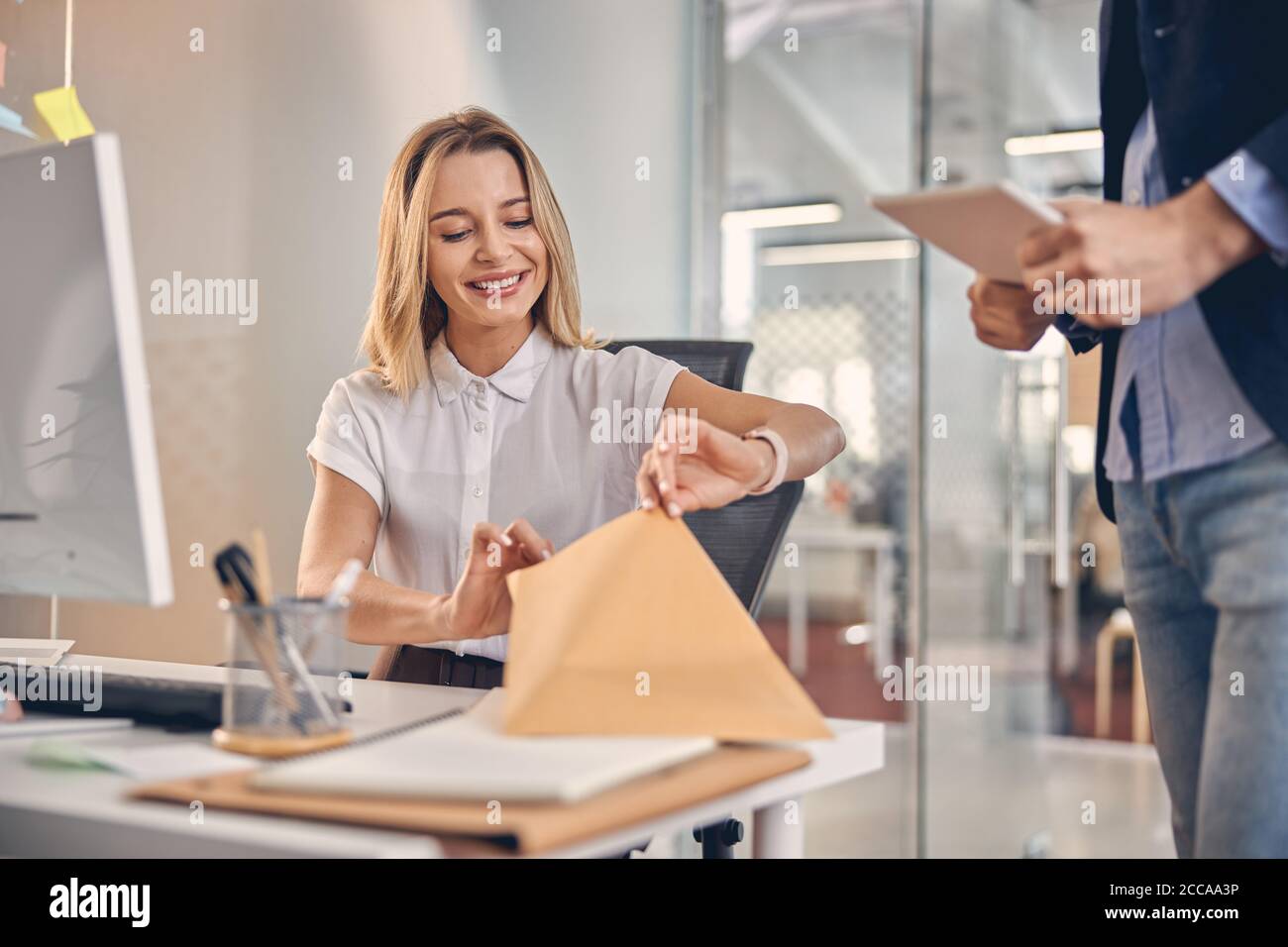 Cheerful young woman checking documents at work Stock Photo - Alamy
