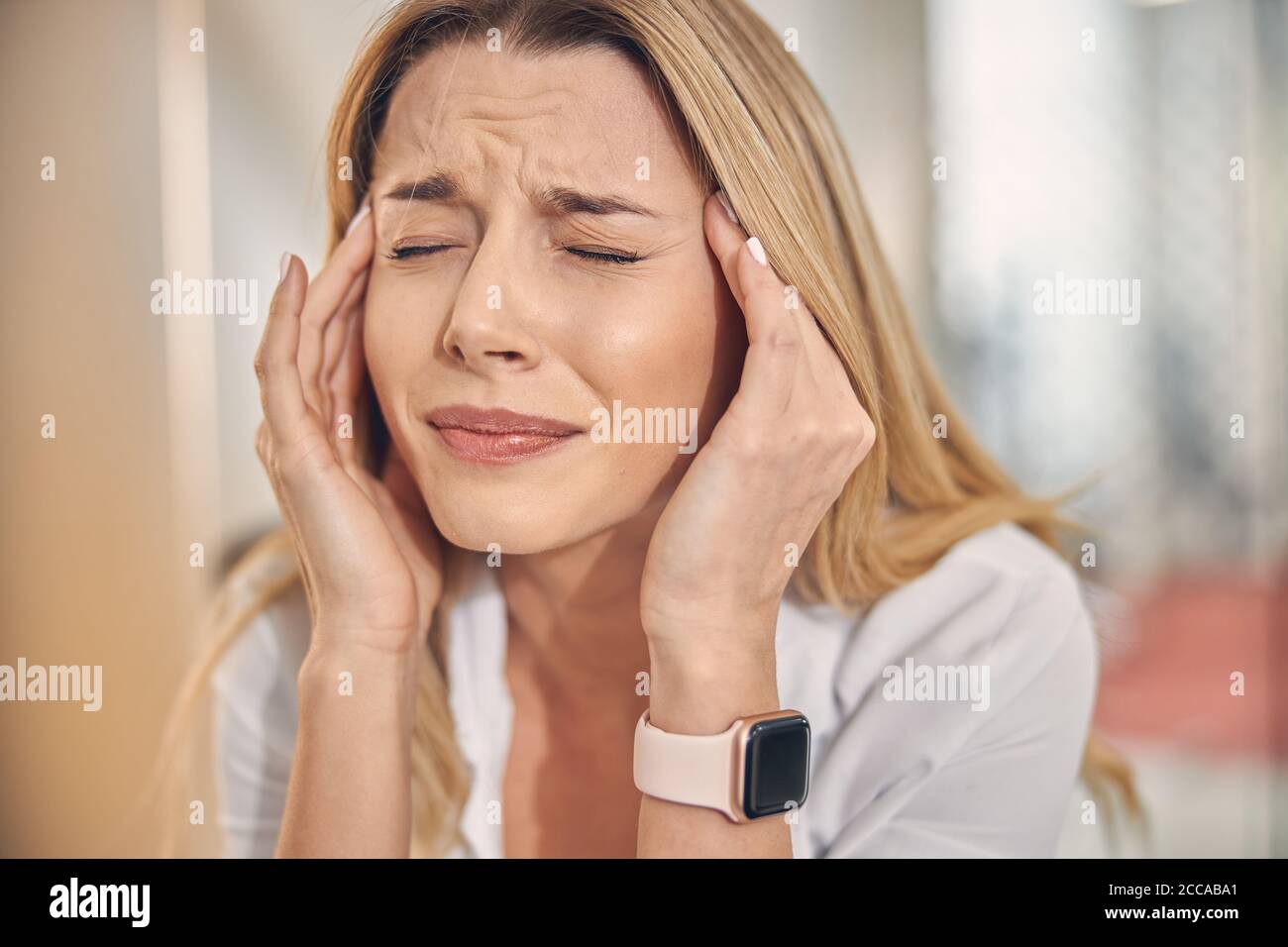 Unhappy young woman touching temples while having headache Stock Photo ...
