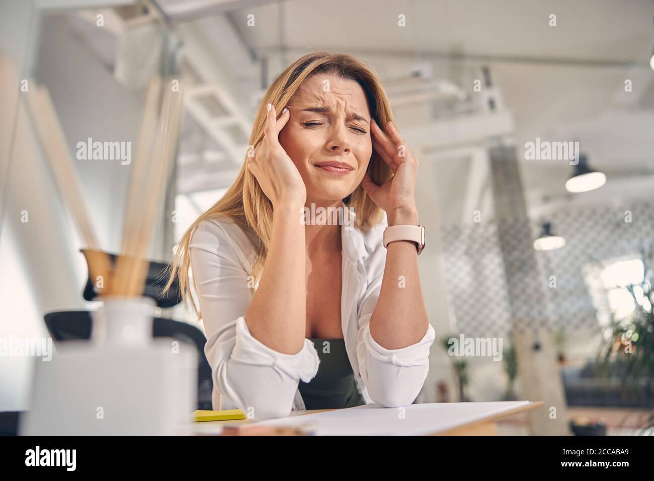 Overworked young woman having headache at work Stock Photo - Alamy