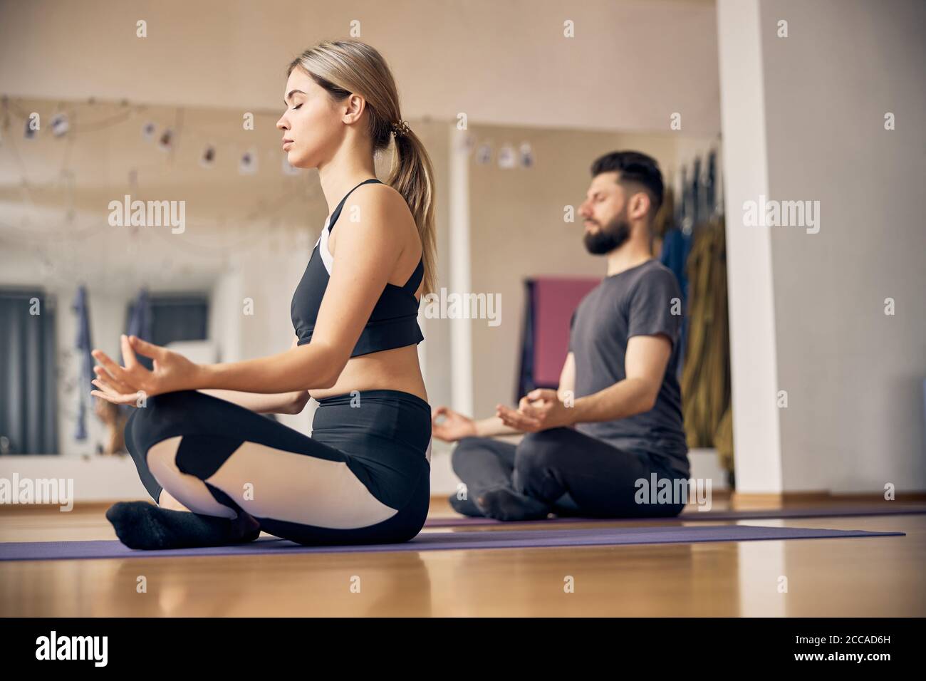 Two fit people sitting cross-legged on the mats Stock Photo - Alamy