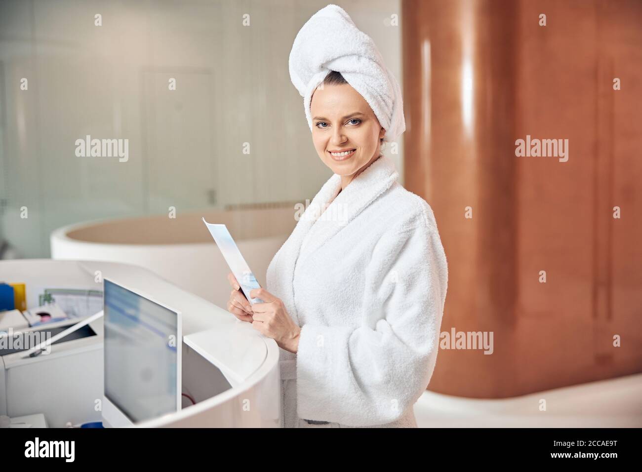 Smiling lady standing at a reception desk Stock Photo - Alamy