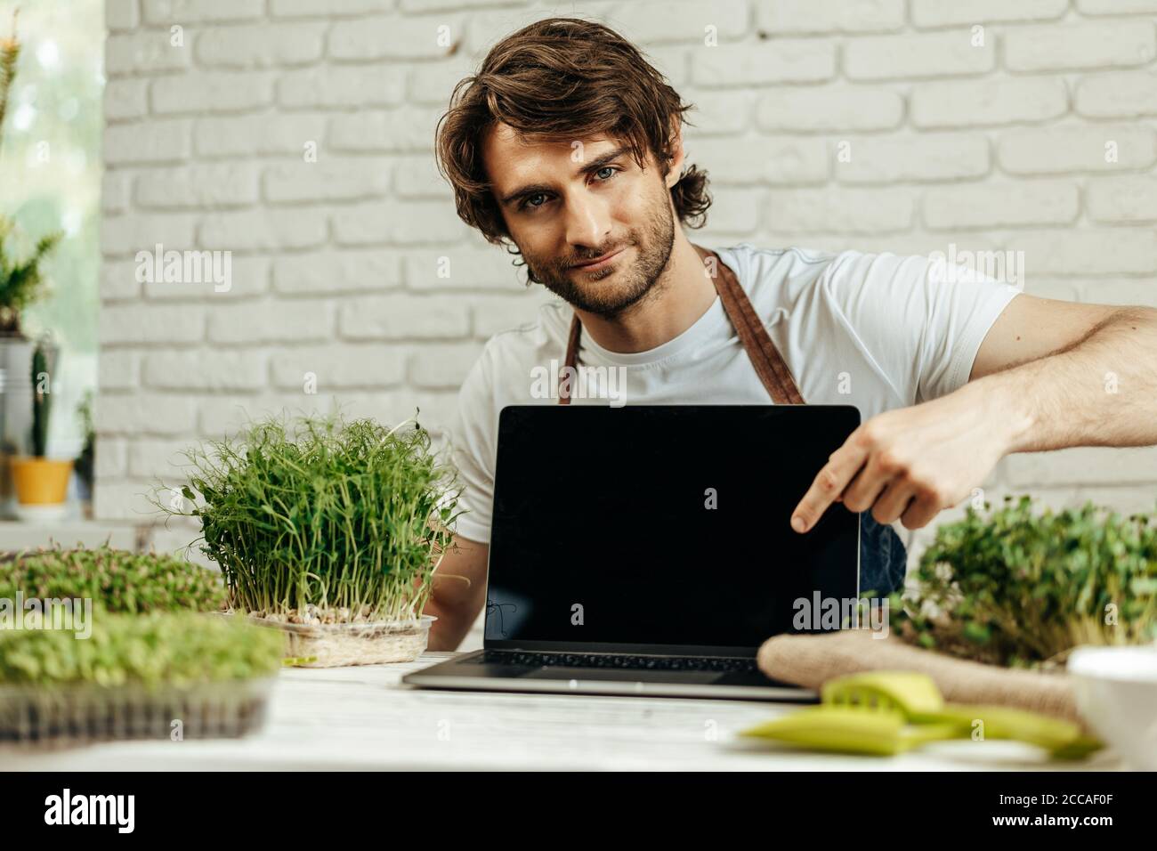 Man farmer shows black screen of laptop and sits at the table with ...