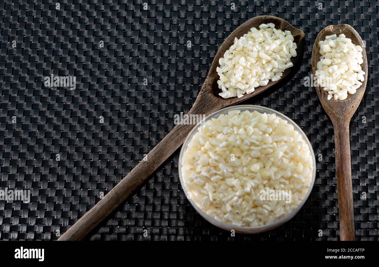 White hominy. White corn served in bowl and wooden spoons. Corn kernels ...