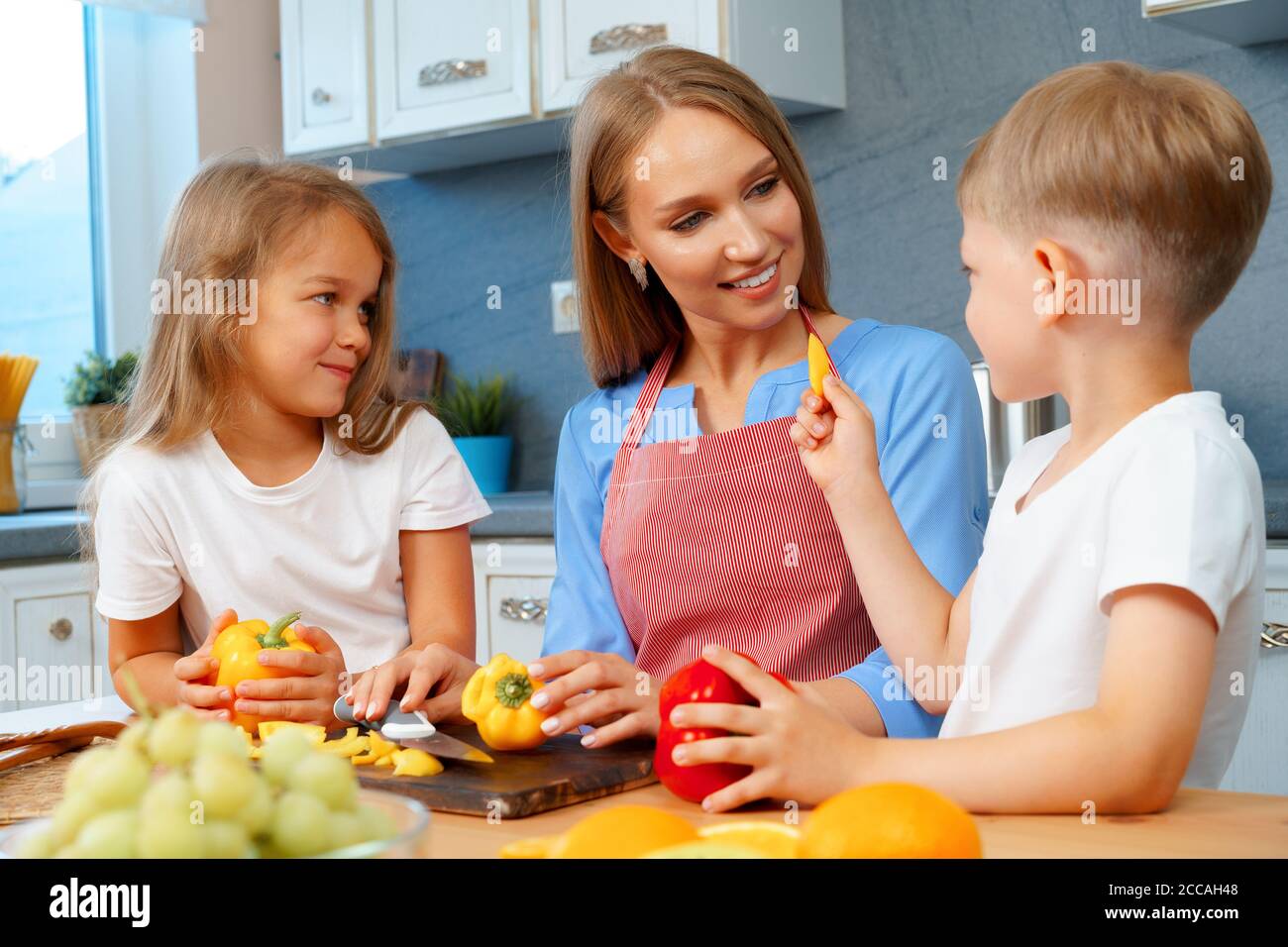 Mother cooking with her children in kitchen Stock Photo - Alamy