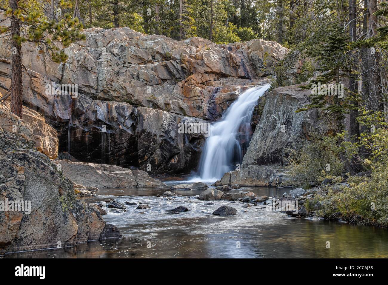 Colorful mountain waterfall into flowing stream Stock Photo - Alamy