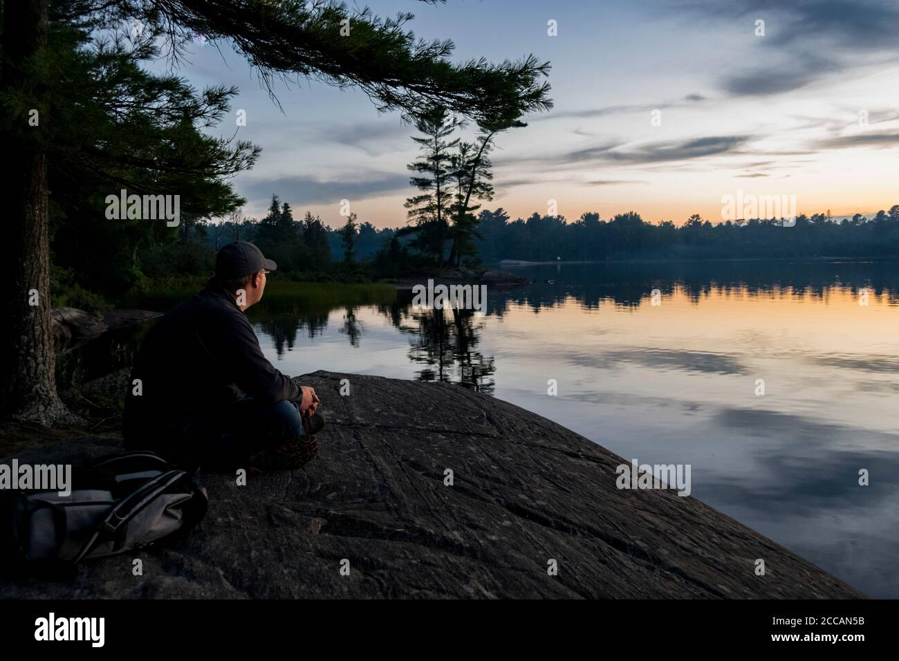 Man sitting on rock Stock Photo - Alamy