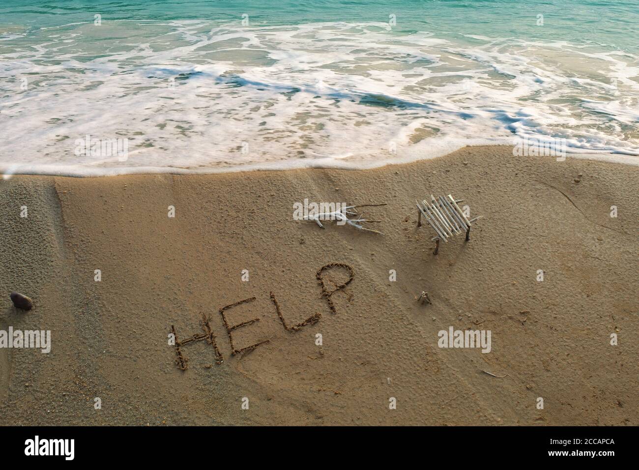 Help written in sand of tropical island beach Stock Photo - Alamy