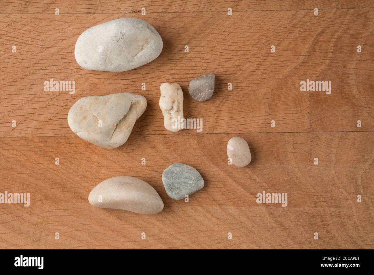 Smooth stones of various sizes are scattered on a wooden board Stock ...