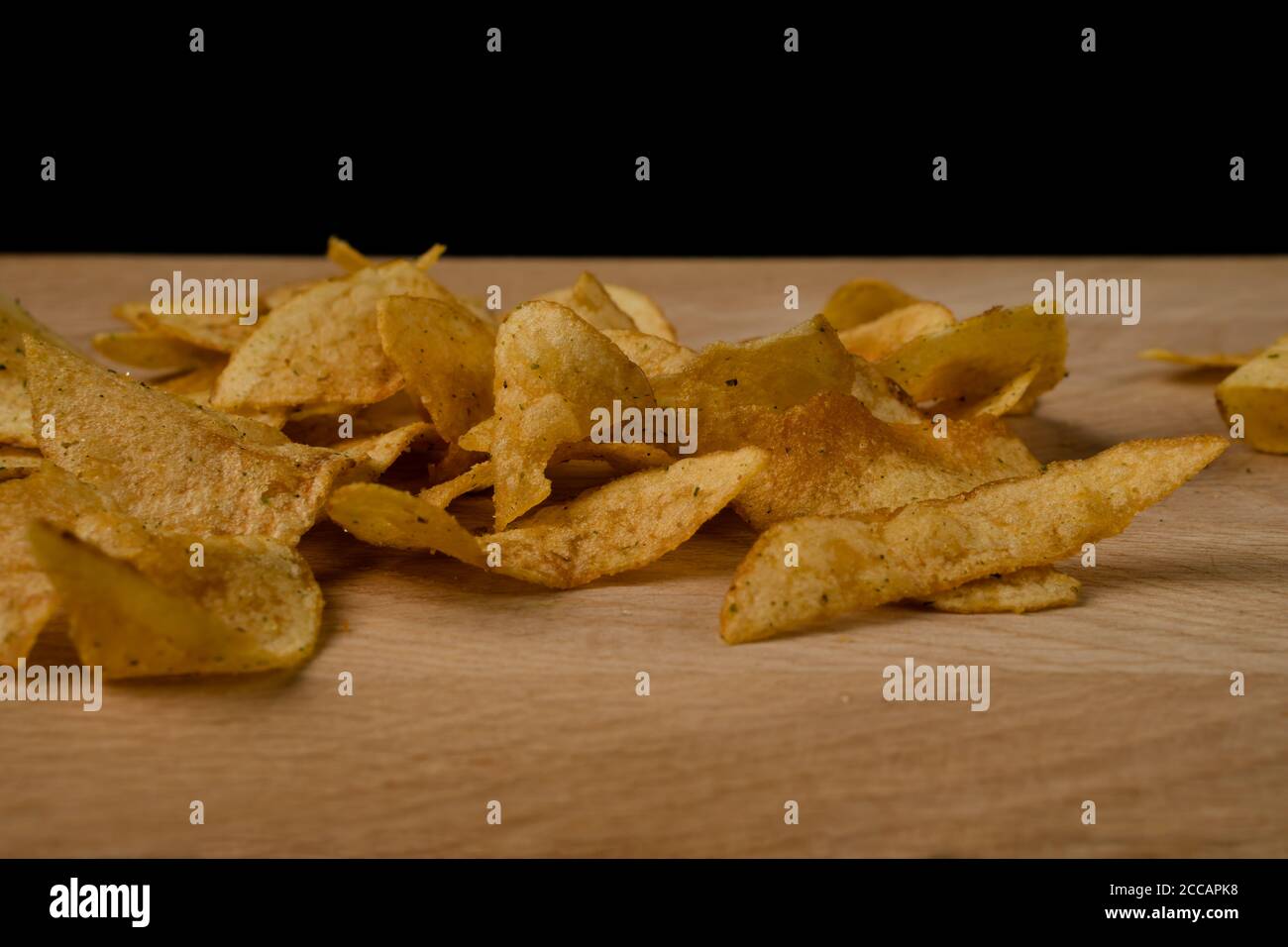 Appetizing potato chips are scattered, on a wooden board Stock Photo ...
