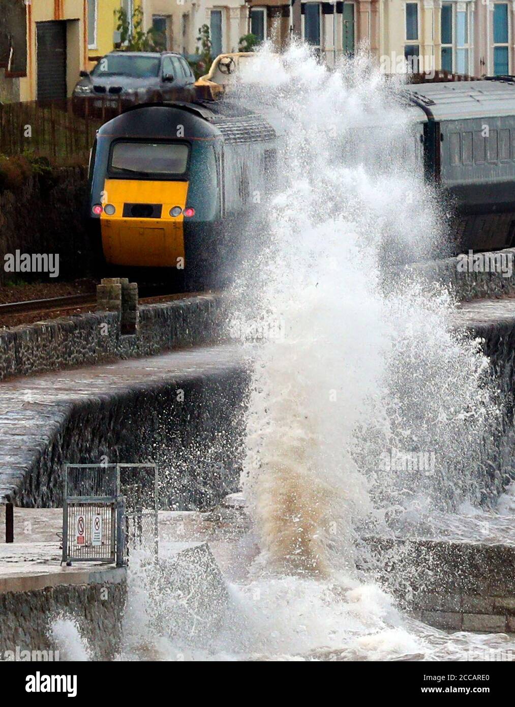 A train passes by strong waves in dawlish hi-res stock photography and ...