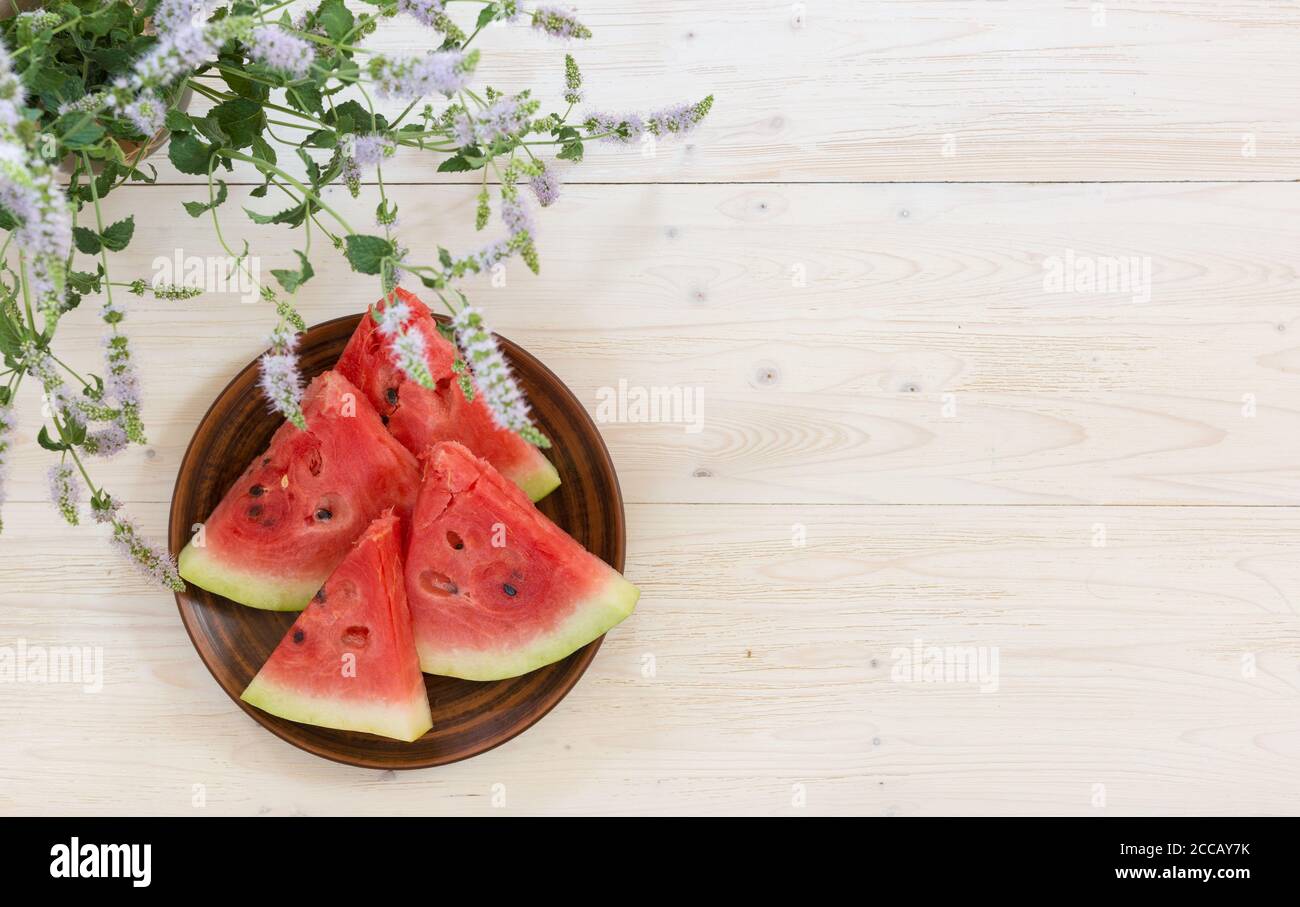 Four slices of ripe watermelon on a plate and a bouquet of blooming ...