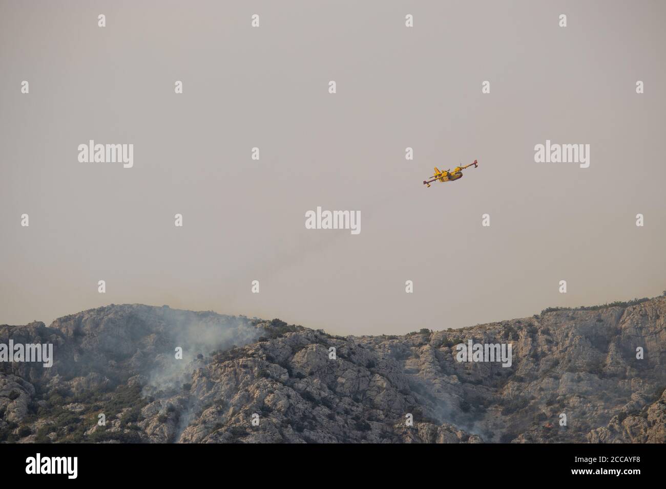 A fire fighting water bomber dropping water on a forest fire on top of ...