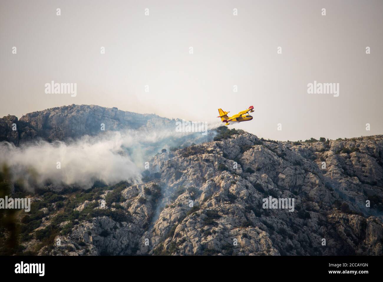 A fire fighting water bomber dropping water on a forest fire on top of ...