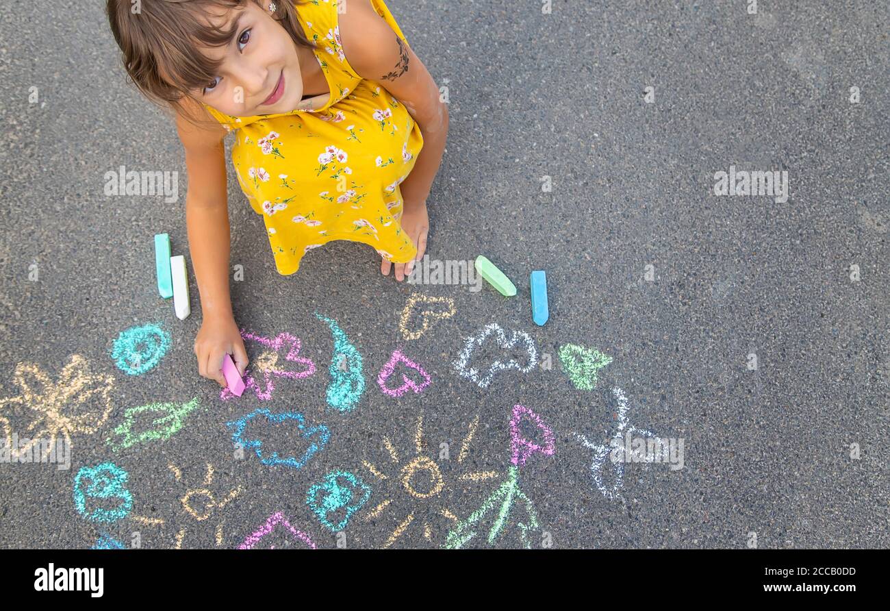 The child draws on the asphalt with chalk. Selective focus. Kid Stock ...