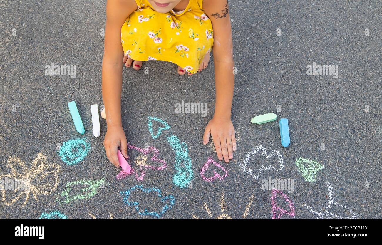 The child draws on the asphalt with chalk. Selective focus. Kid Stock ...