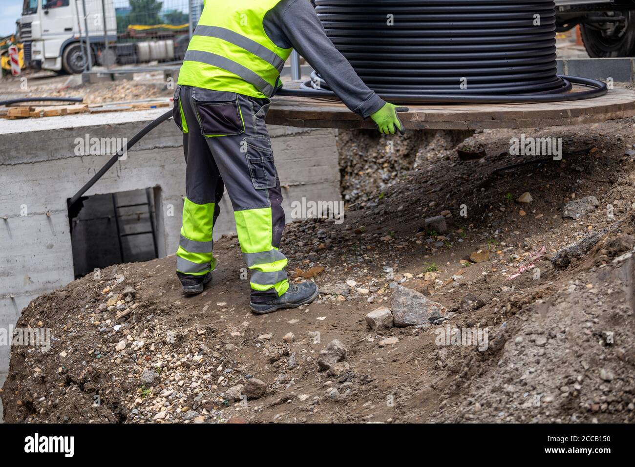 Workers unrolls black wire electrical cable with wooden coil. Laying ...