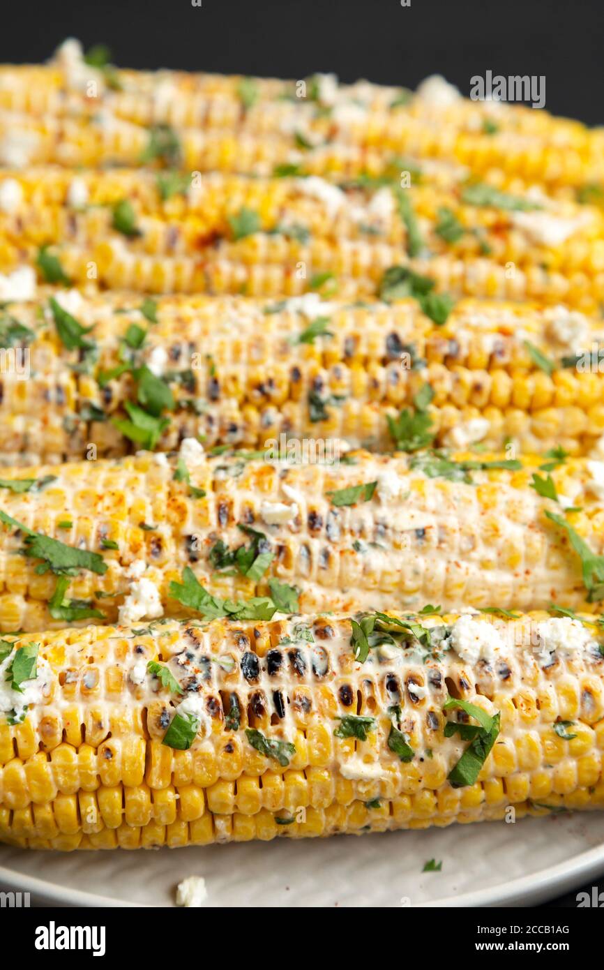 Homemade Elote Mexican Street Corn on a plate on a black background ...