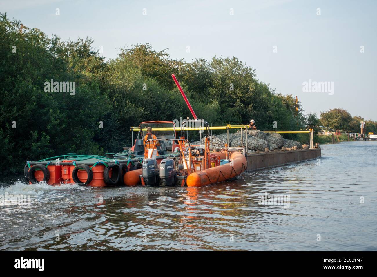CRT canal and river maintenance workers pushing river supplies barge ...