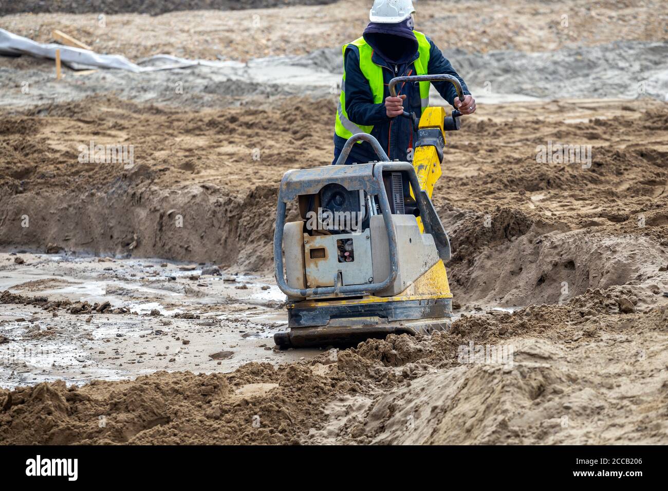 Walk behind vibrating machine is compacting soil at the construction ...