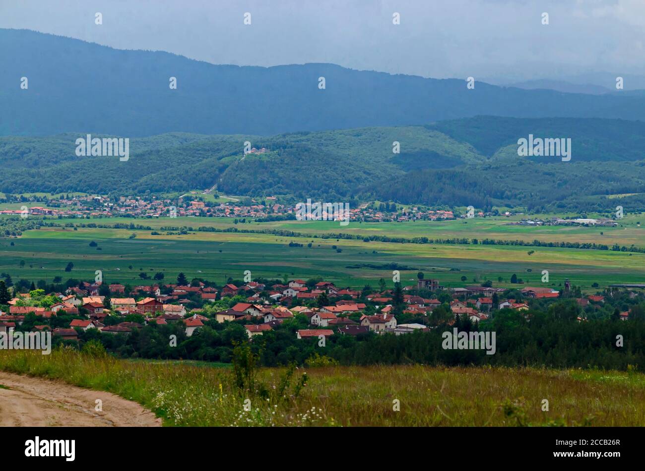 Summer scene with meadow, forest, the Bulgarian villages Alino, Belchin ...